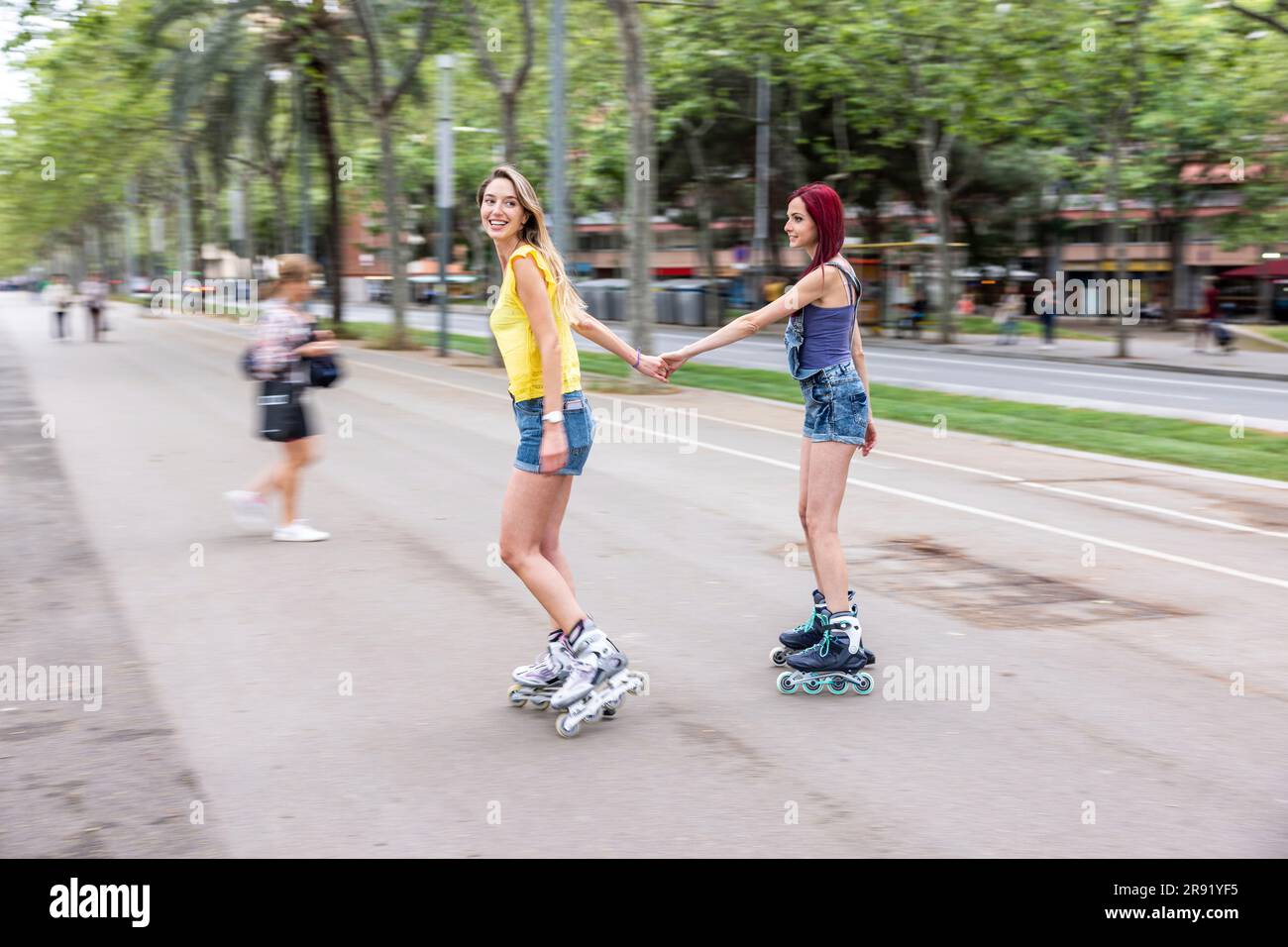 Friends wearing inline skate skating on street Stock Photo - Alamy