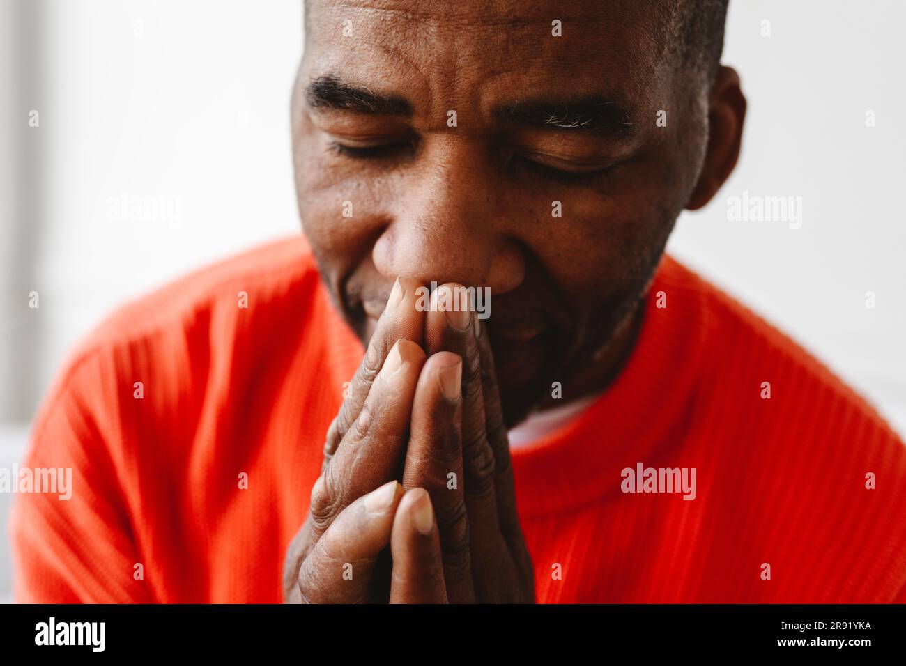 Mature man praying with hands clasped and eyes closed Stock Photo - Alamy