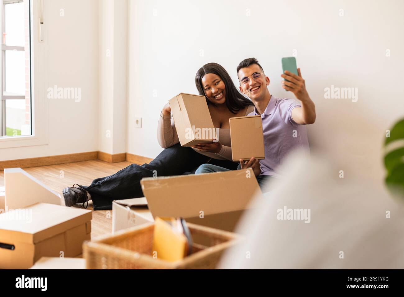 Happy couple taking selfie with cardboard boxes in new home Stock Photo ...