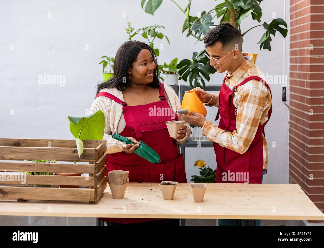 Couple watering containers with soil on balcony Stock Photo - Alamy