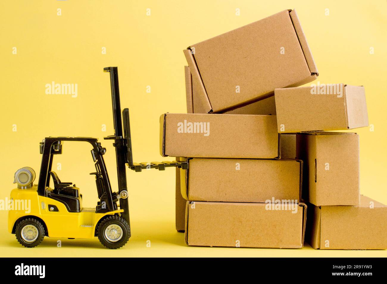 Forklift truck raises cardboard boxes on a yellow background. Cargo ...