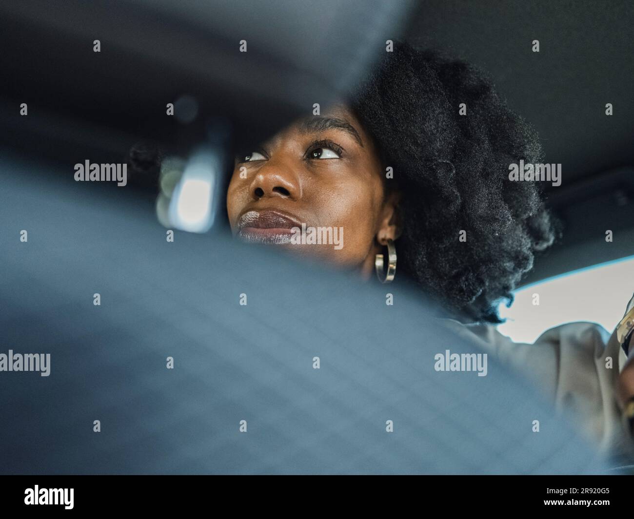 Contemplative woman with curly hair in car Stock Photo - Alamy