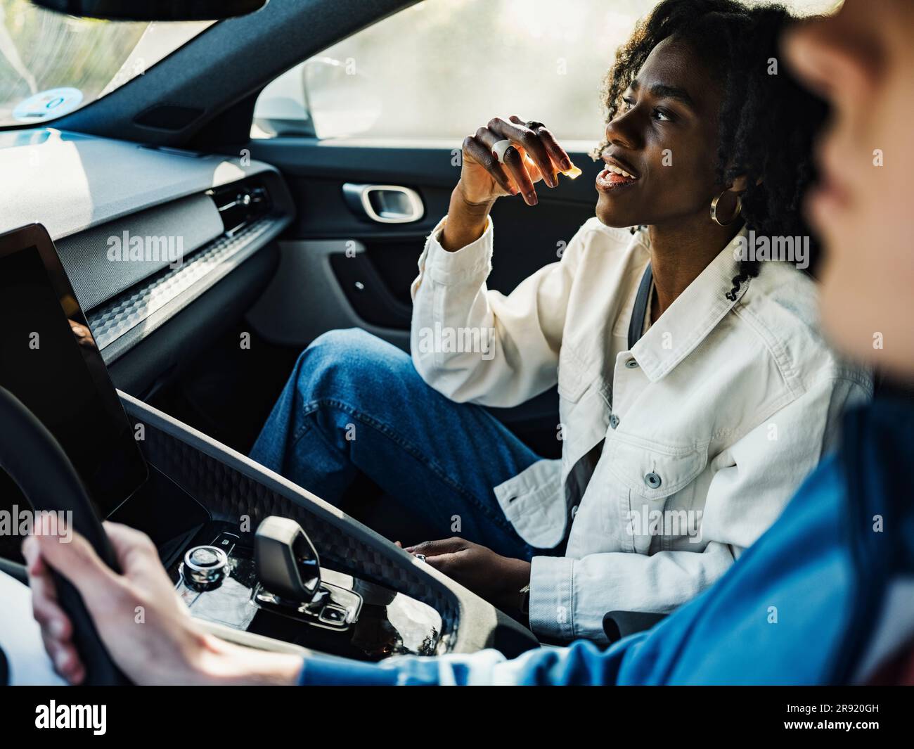 Woman having candy sitting with friend in car Stock Photo - Alamy
