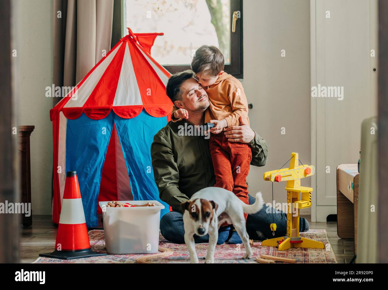Son kissing father sitting near by dog at home Stock Photo - Alamy