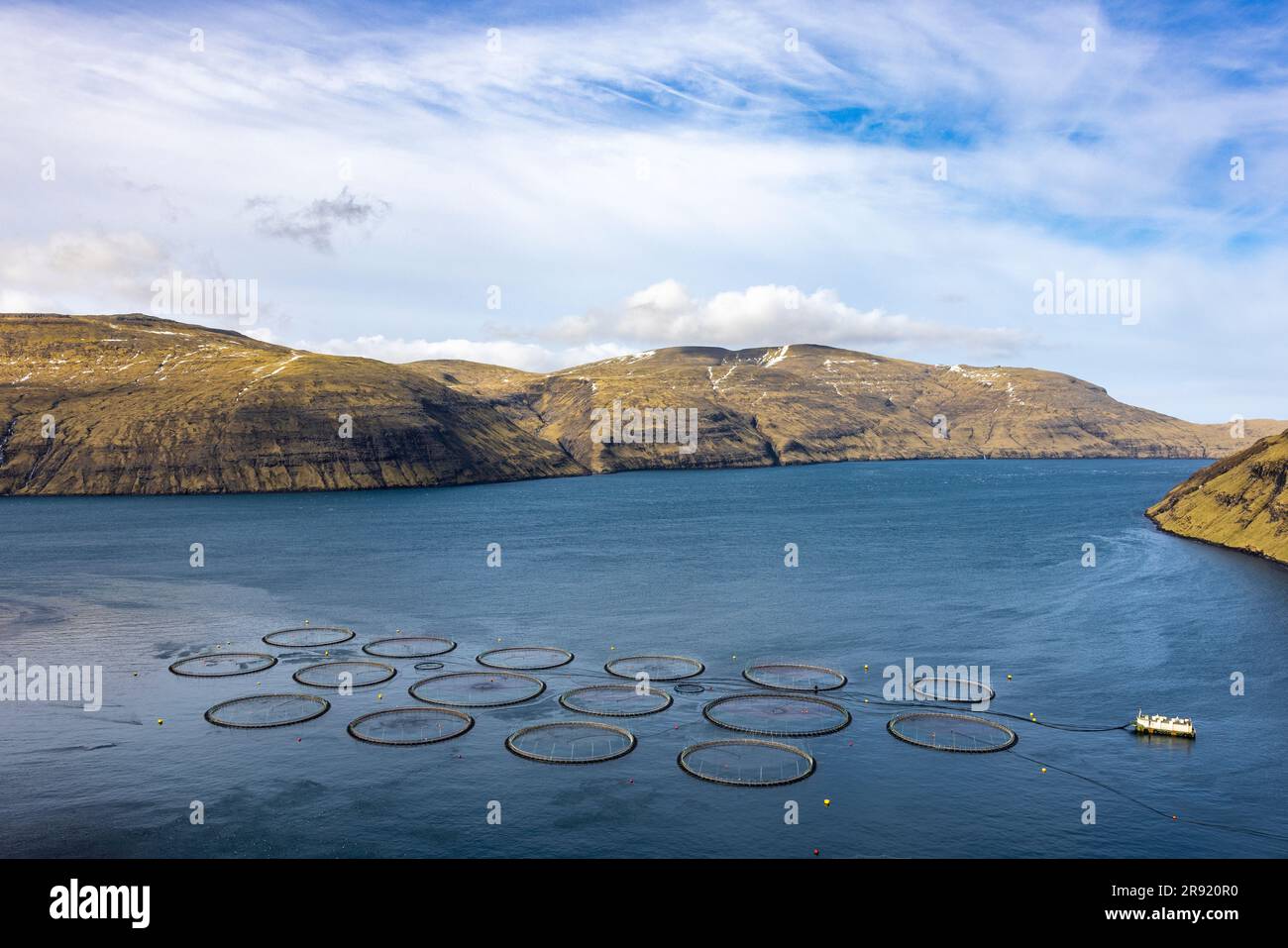 Salmon fish farm in ocean water near mountain at the coast of Streymy ...