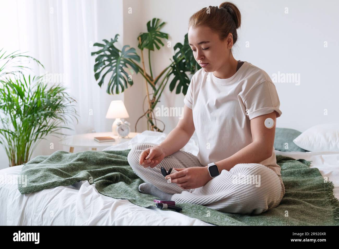 Woman with diabetes sitting cross-legged on bed at home Stock Photo - Alamy
