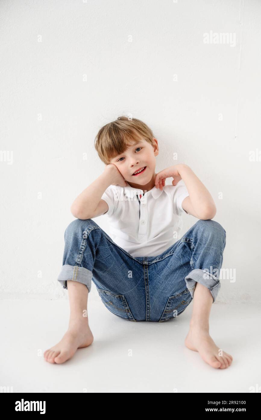 Boy sitting in front of white backdrop Stock Photo - Alamy