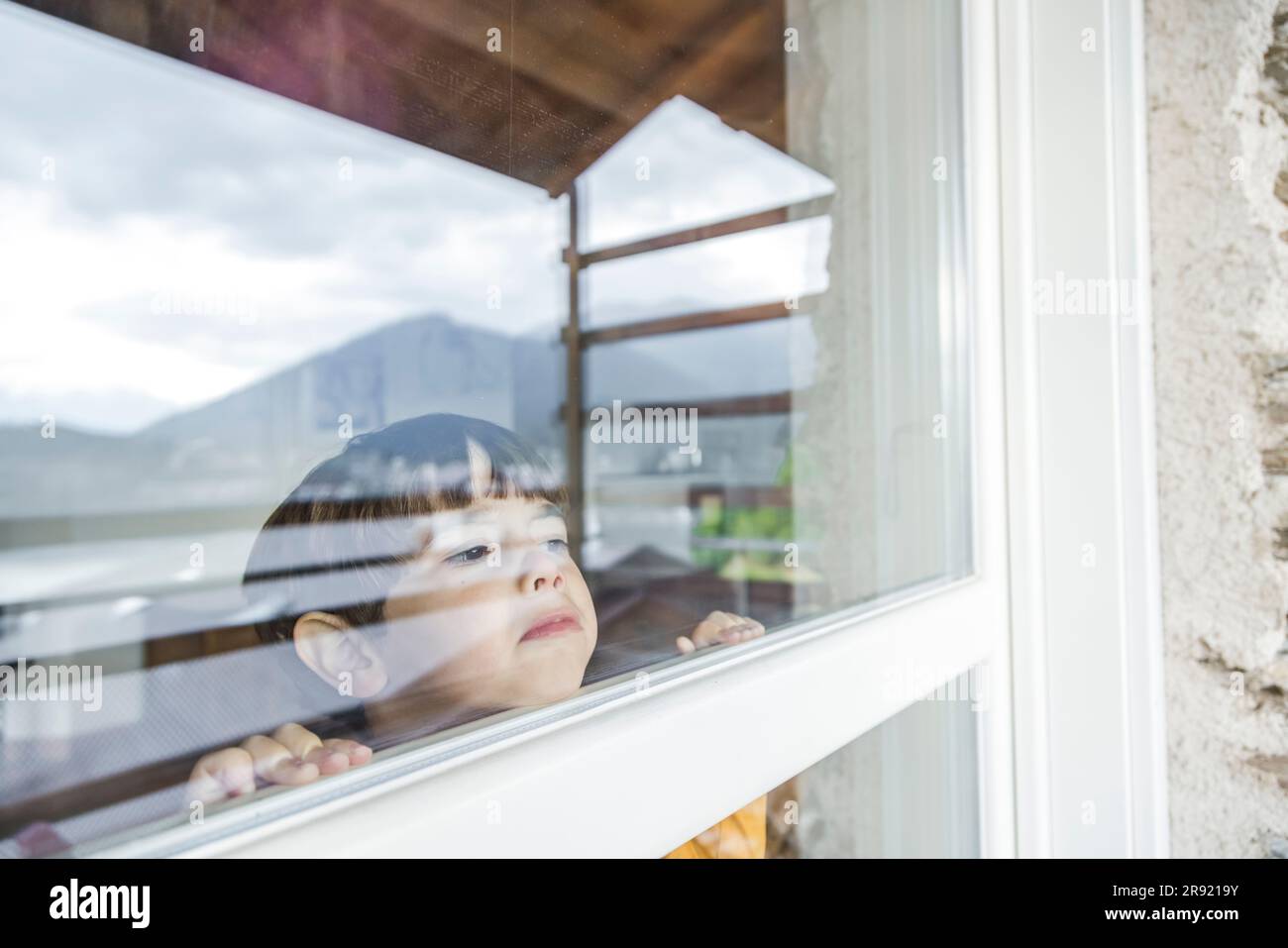 Boy looking out of window Stock Photo - Alamy