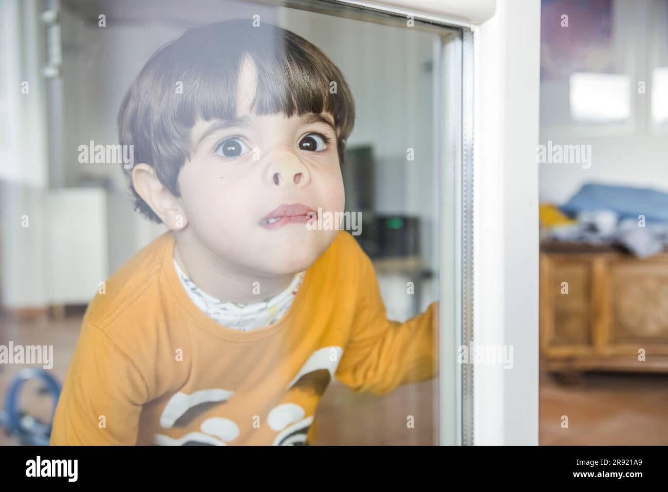 Boy pressing nose against window Stock Photo - Alamy