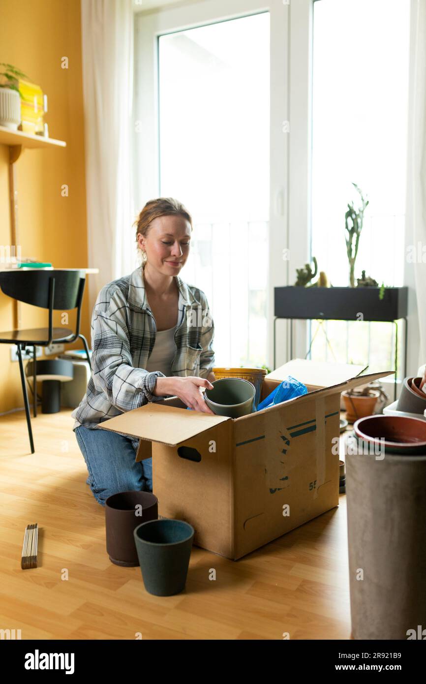 Woman unpacking containers from cardboard box Stock Photo - Alamy