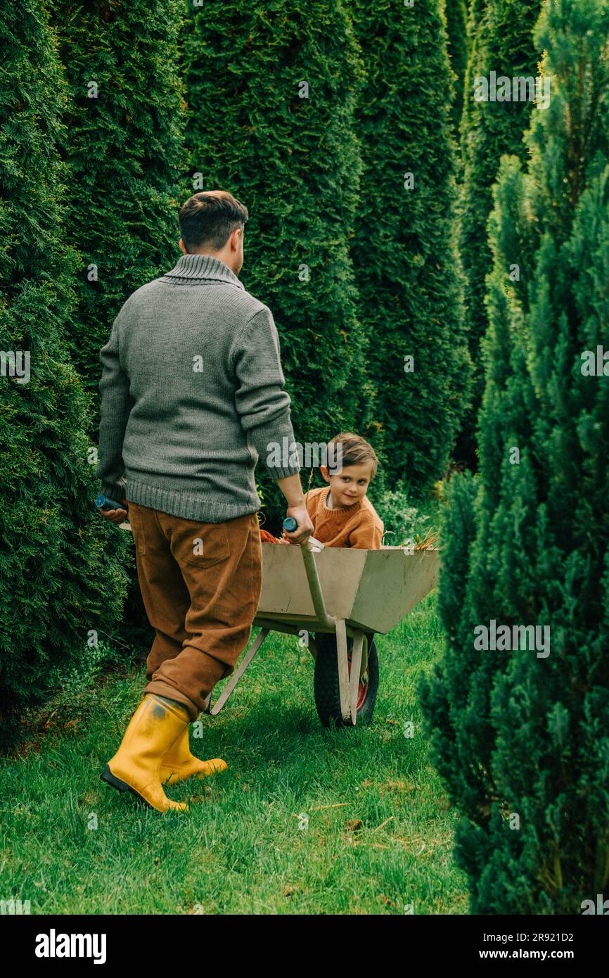 Father pushing son sitting in wheelbarrow at back yard Stock Photo - Alamy