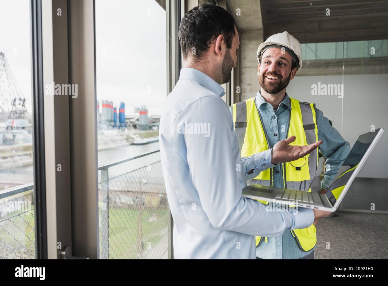 Happy building contractor discussing with architect at site Stock Photo ...