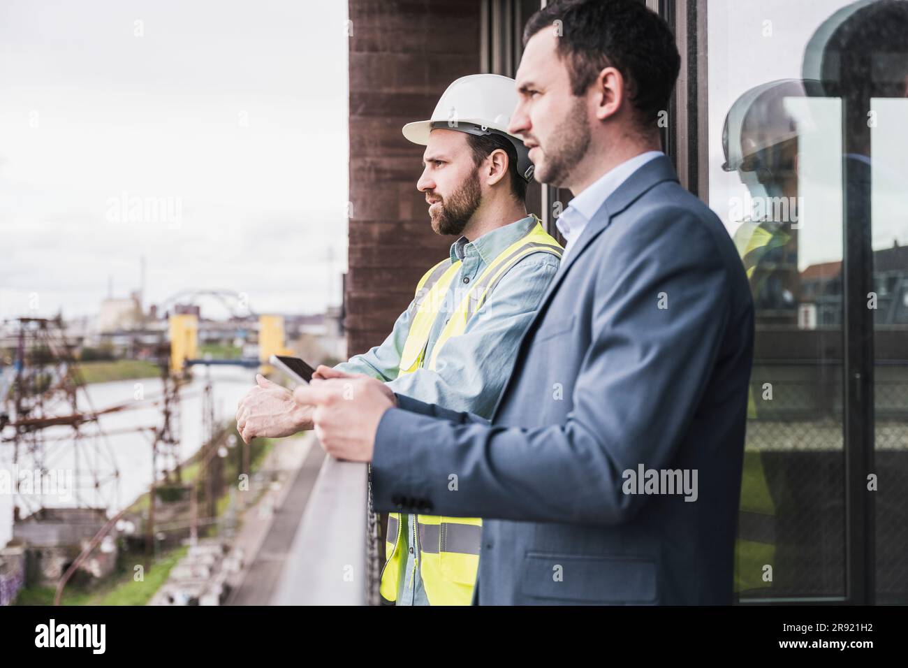 Architect and building contractor standing near railing Stock Photo - Alamy
