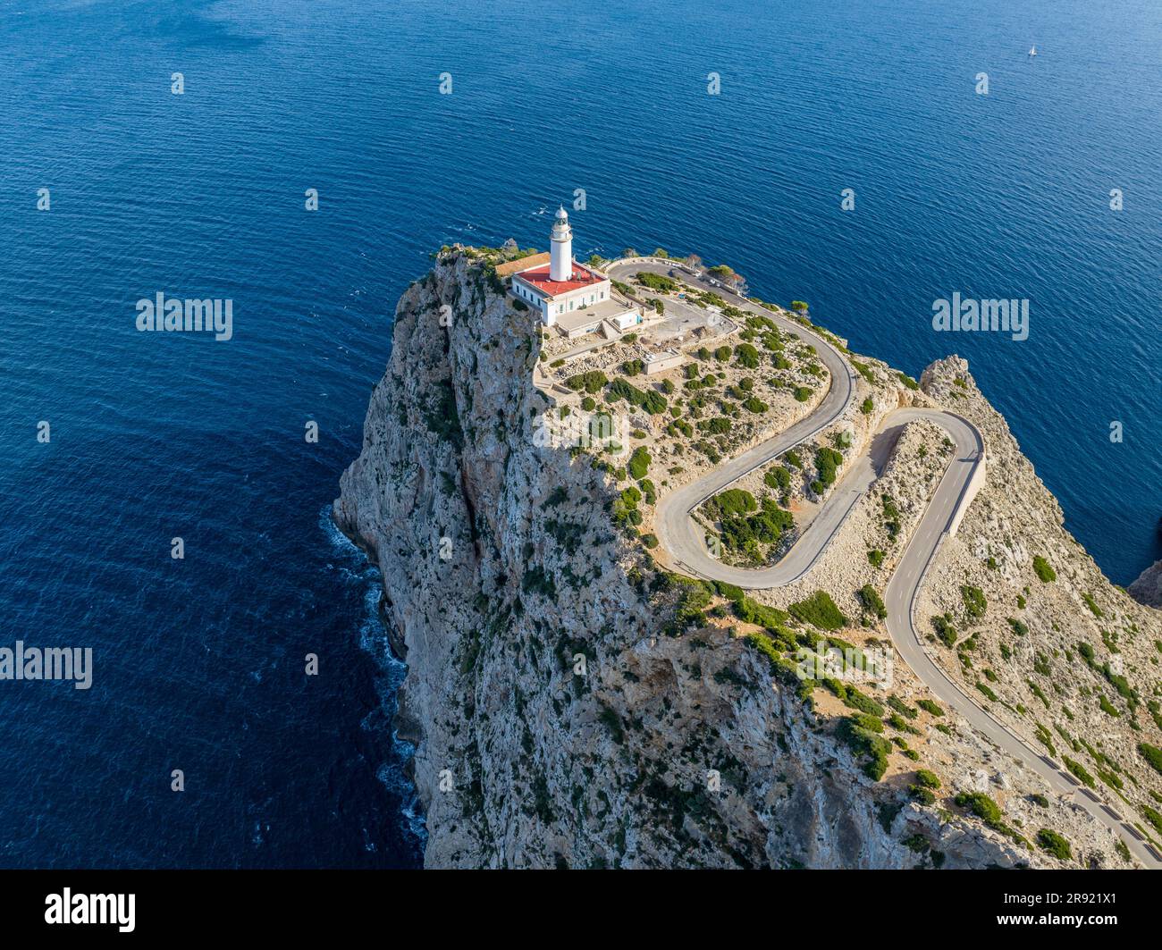 Winding road leading towards lighthouse on Cabo Formentor cliff amidst ...