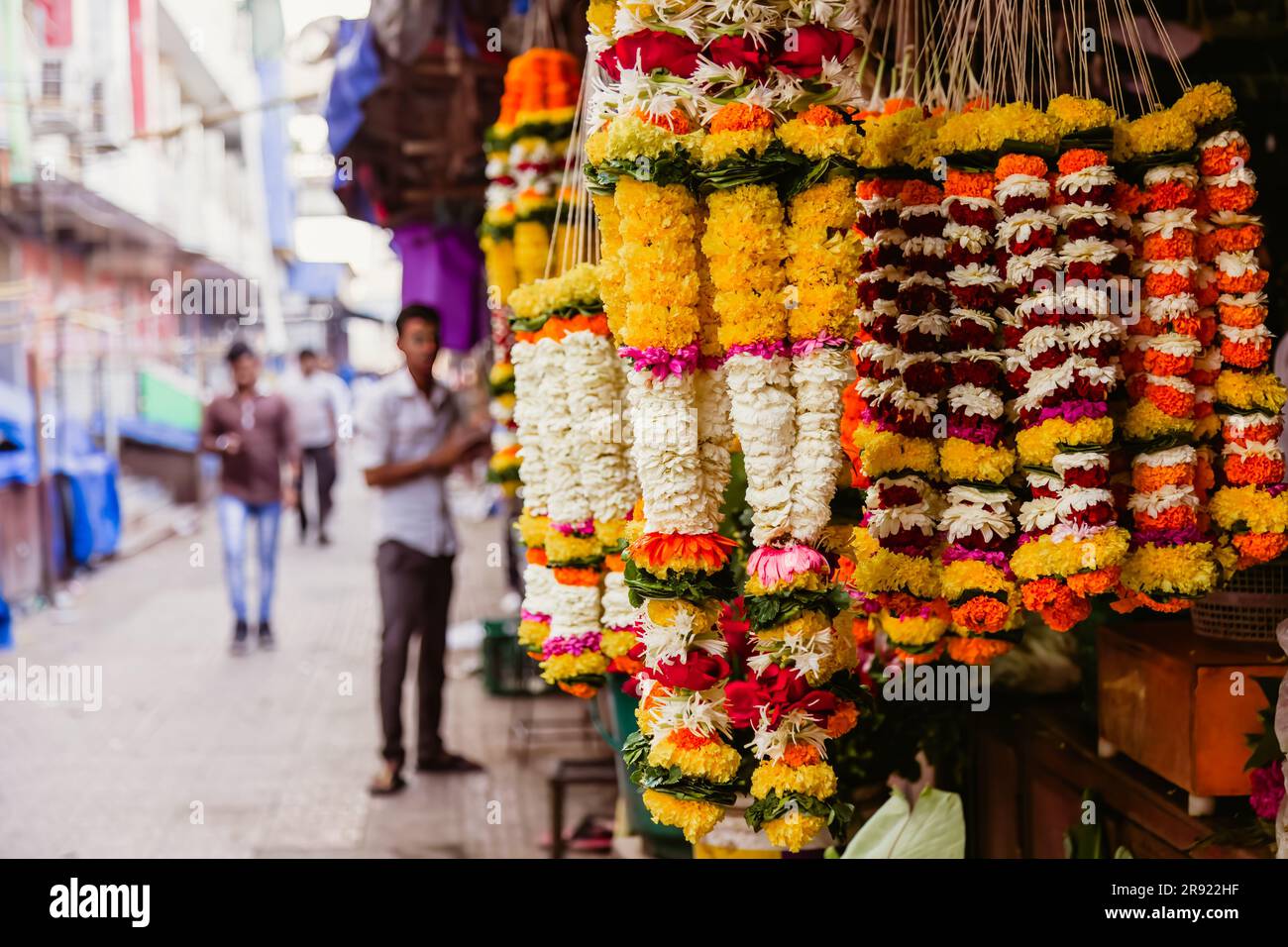 A vibrant street scene of a flower seller at a busy railway station in ...