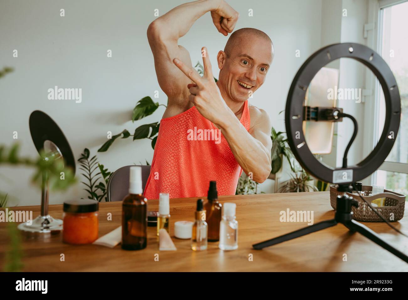 Smiling man flexing muscle and making vlog at home Stock Photo - Alamy
