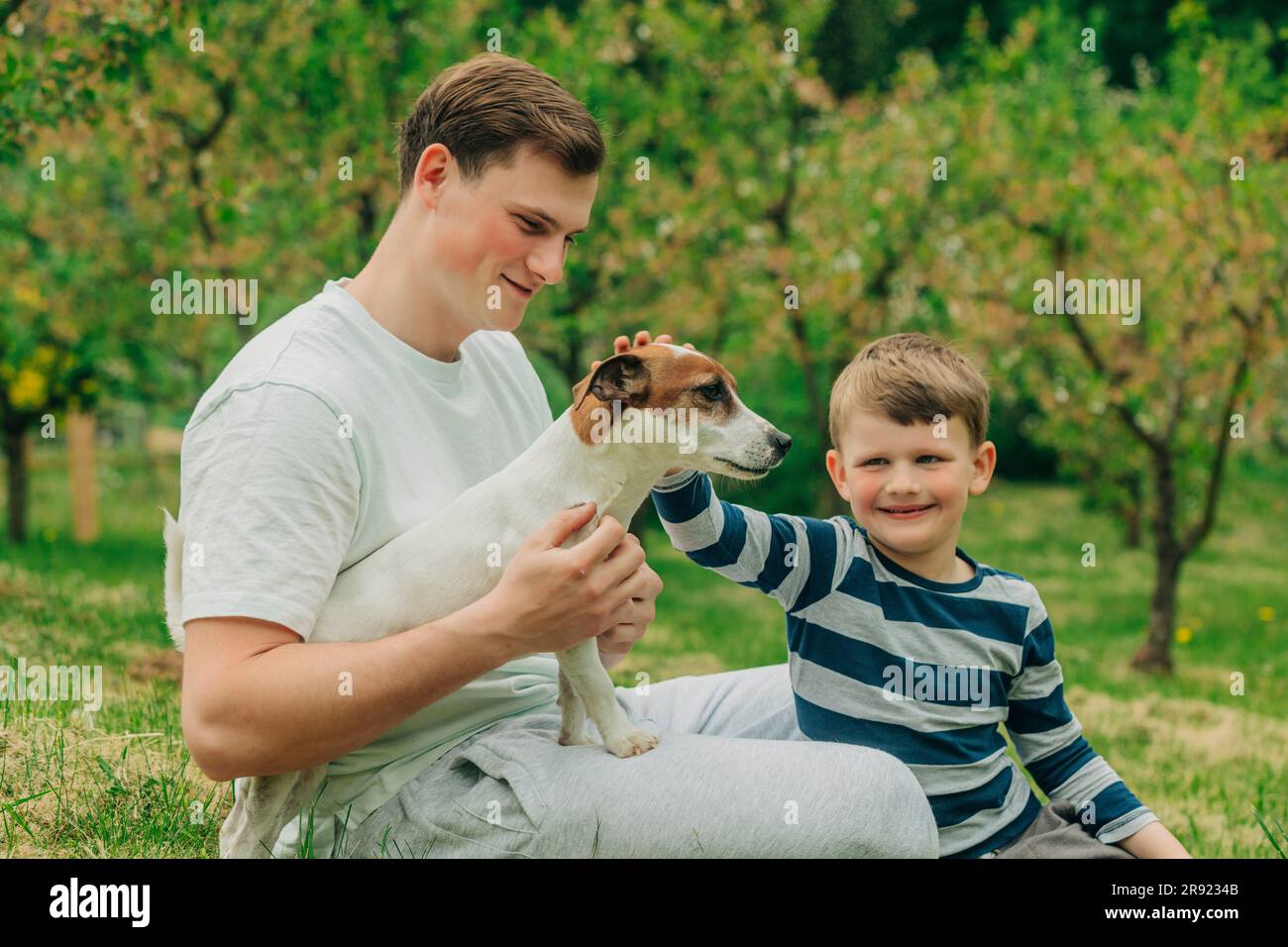 Happy father with son stroking Jack Russell Terrier dog in garden Stock ...