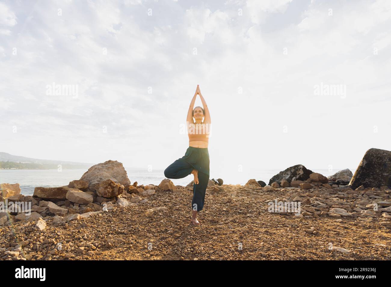 Woman practicing tree pose at beach Stock Photo - Alamy