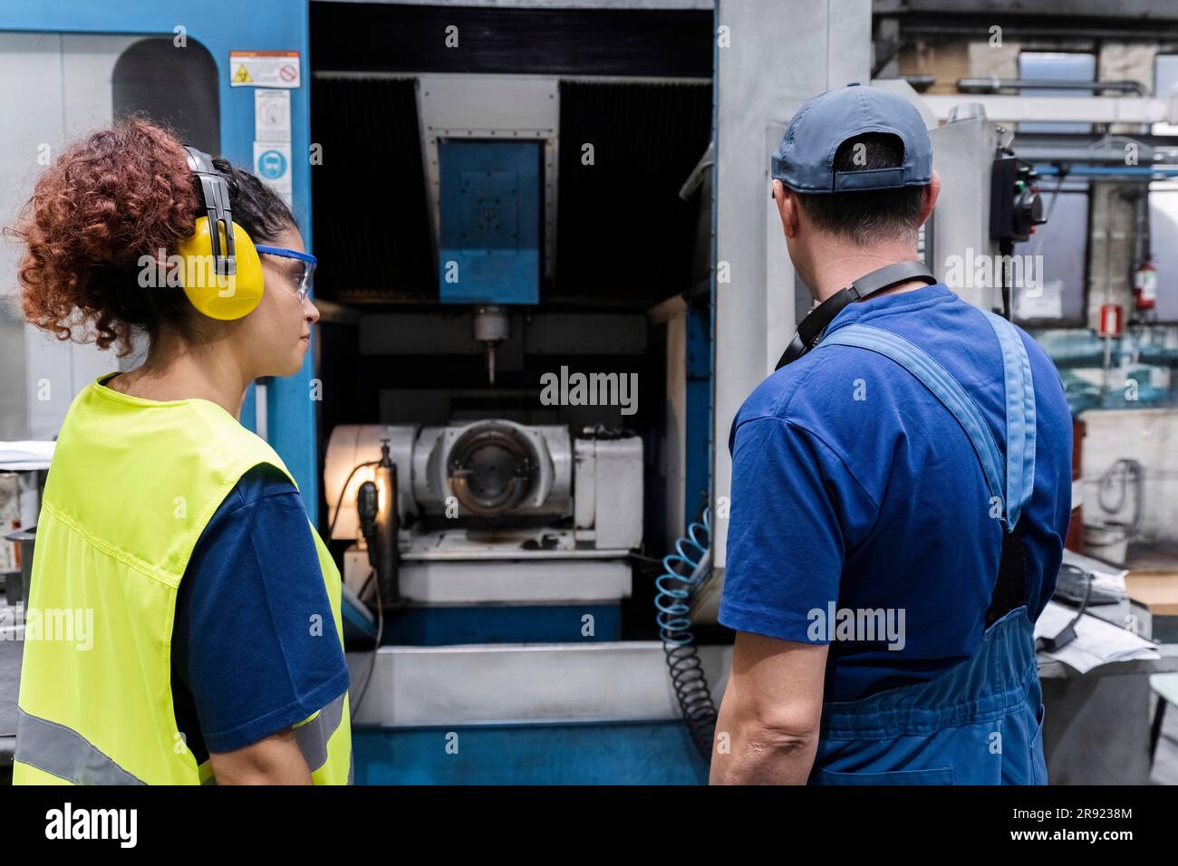 Maintenance engineer examining coworker working in modern factory Stock ...