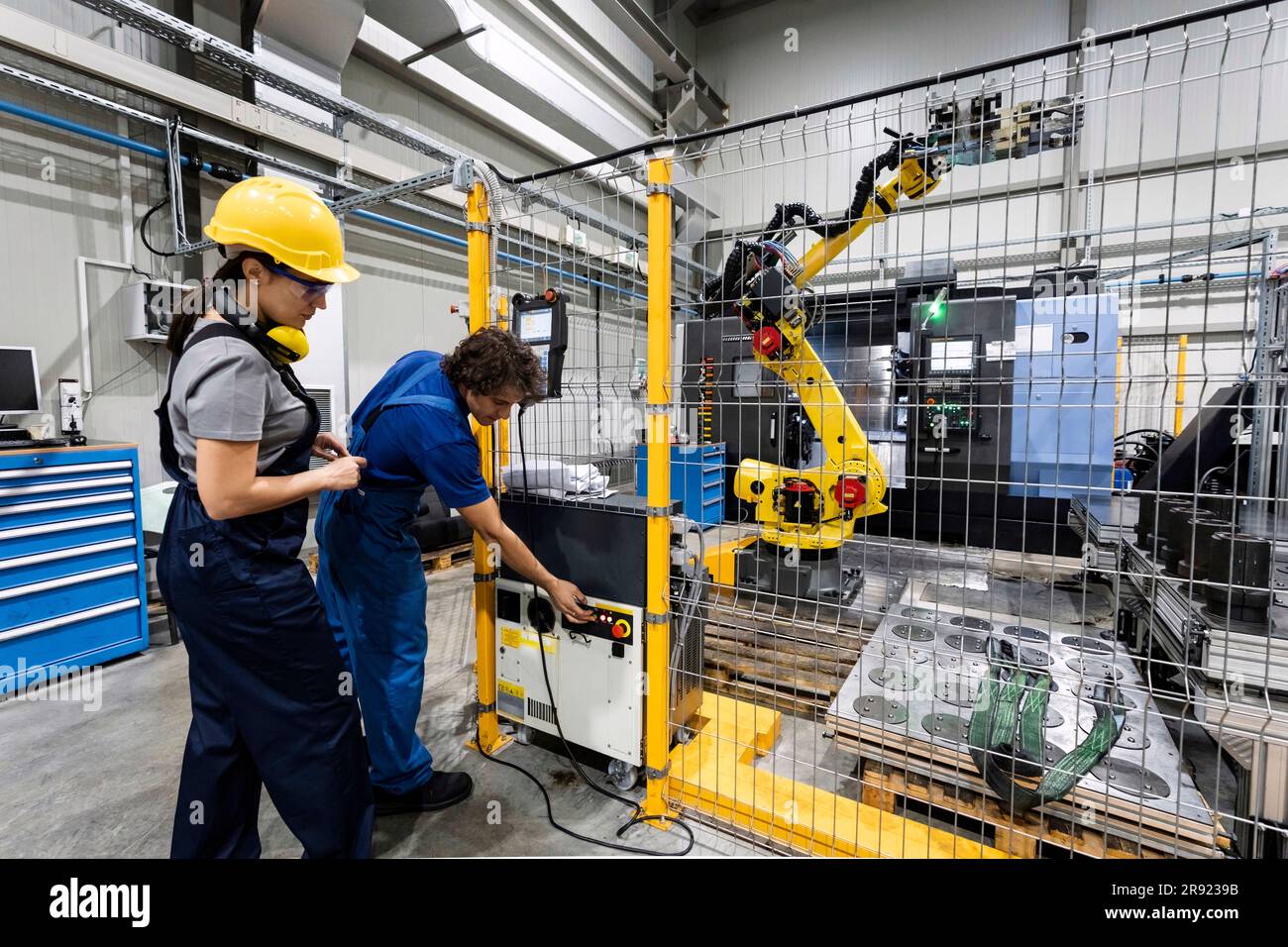 Maintenance engineers operating robotic arm in modern factory Stock ...