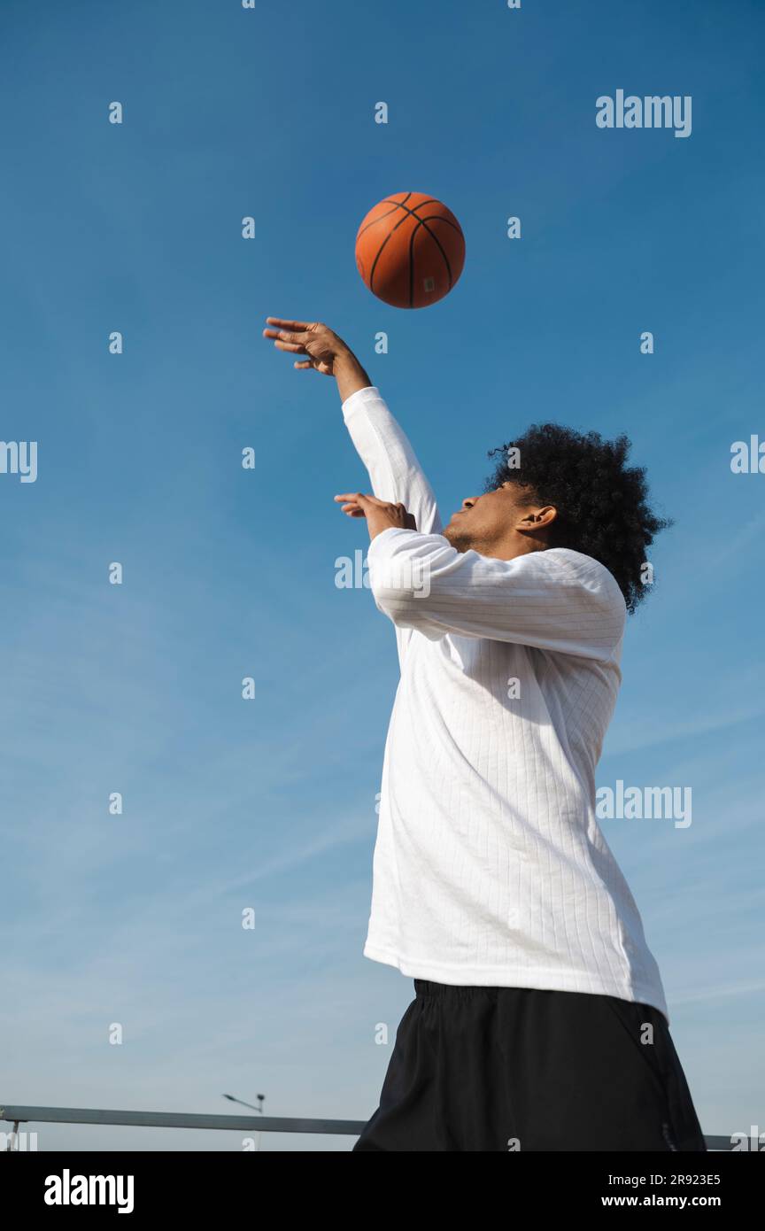 Athlete throwing basketball under sky Stock Photo - Alamy
