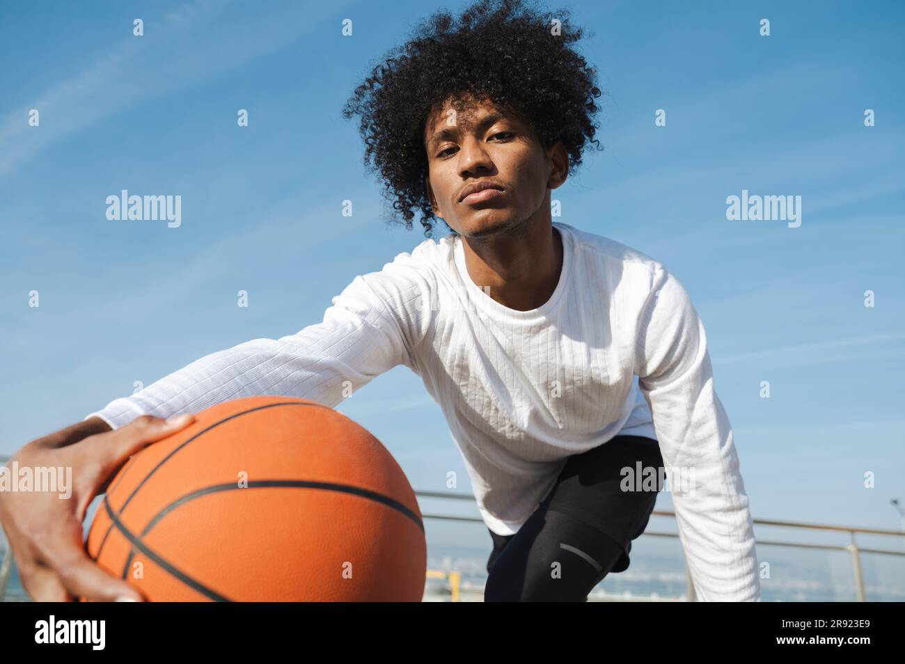 Confident athlete with curly hair playing basketball Stock Photo - Alamy