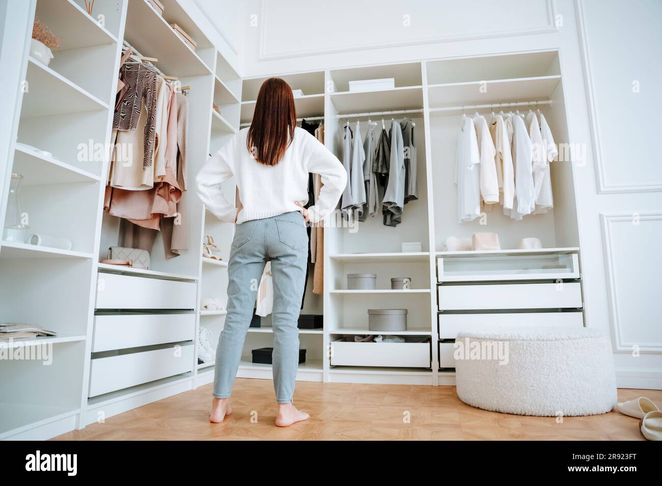 Woman with arms akimbo looking at her clothes in wardrobe Stock Photo ...