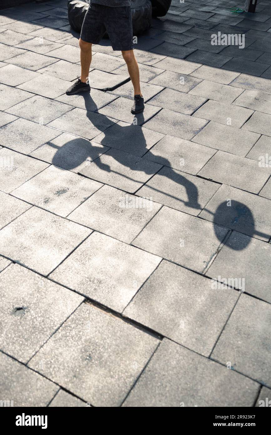Shadow of man lifting weights exercising at rooftop gym Stock Photo - Alamy