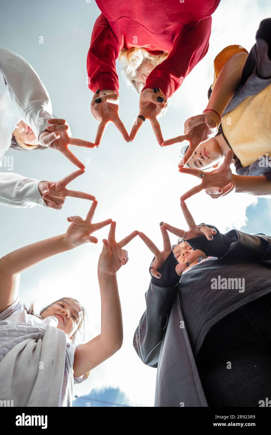 Happy friends making star shape with fingers Stock Photo - Alamy
