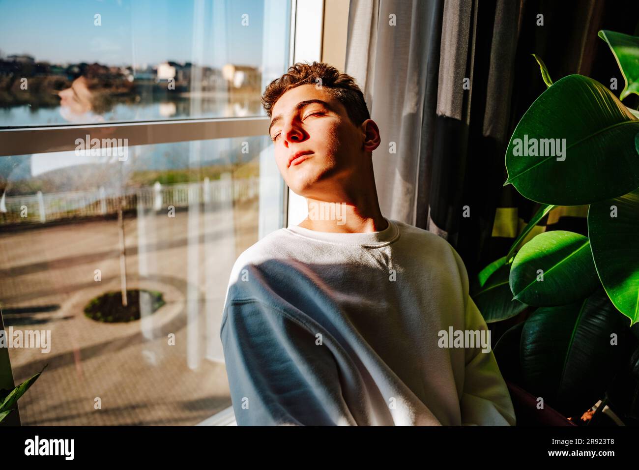 Boy with eyes closed leaning on window at home Stock Photo - Alamy