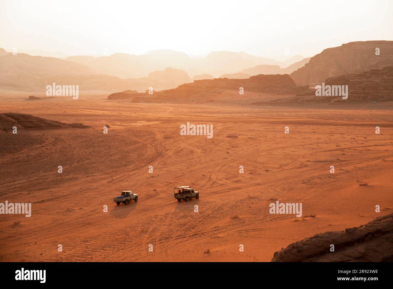 Cars on dirt road in desert at sunset Stock Photo - Alamy