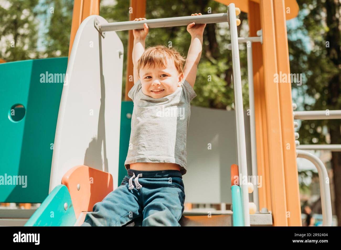 Boy hanging on slide in playground Stock Photo - Alamy