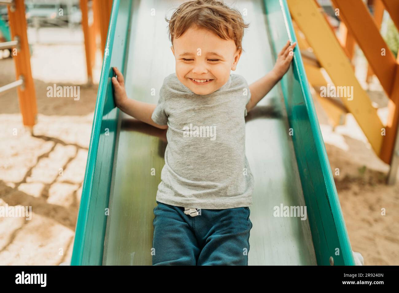 Cheerful boy having fun on slide in playground Stock Photo - Alamy