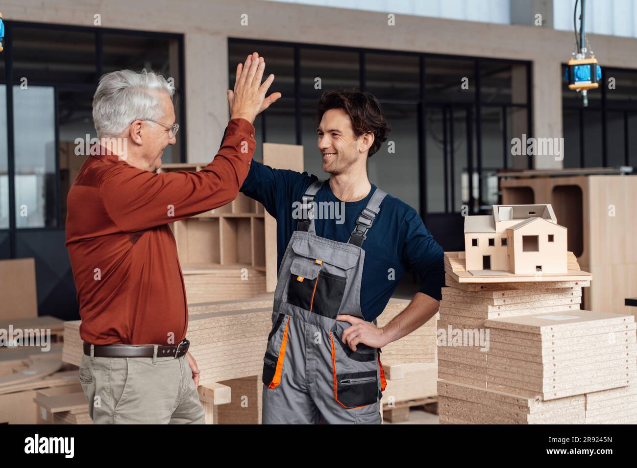 Happy businessman giving high-five to each other in industry Stock ...