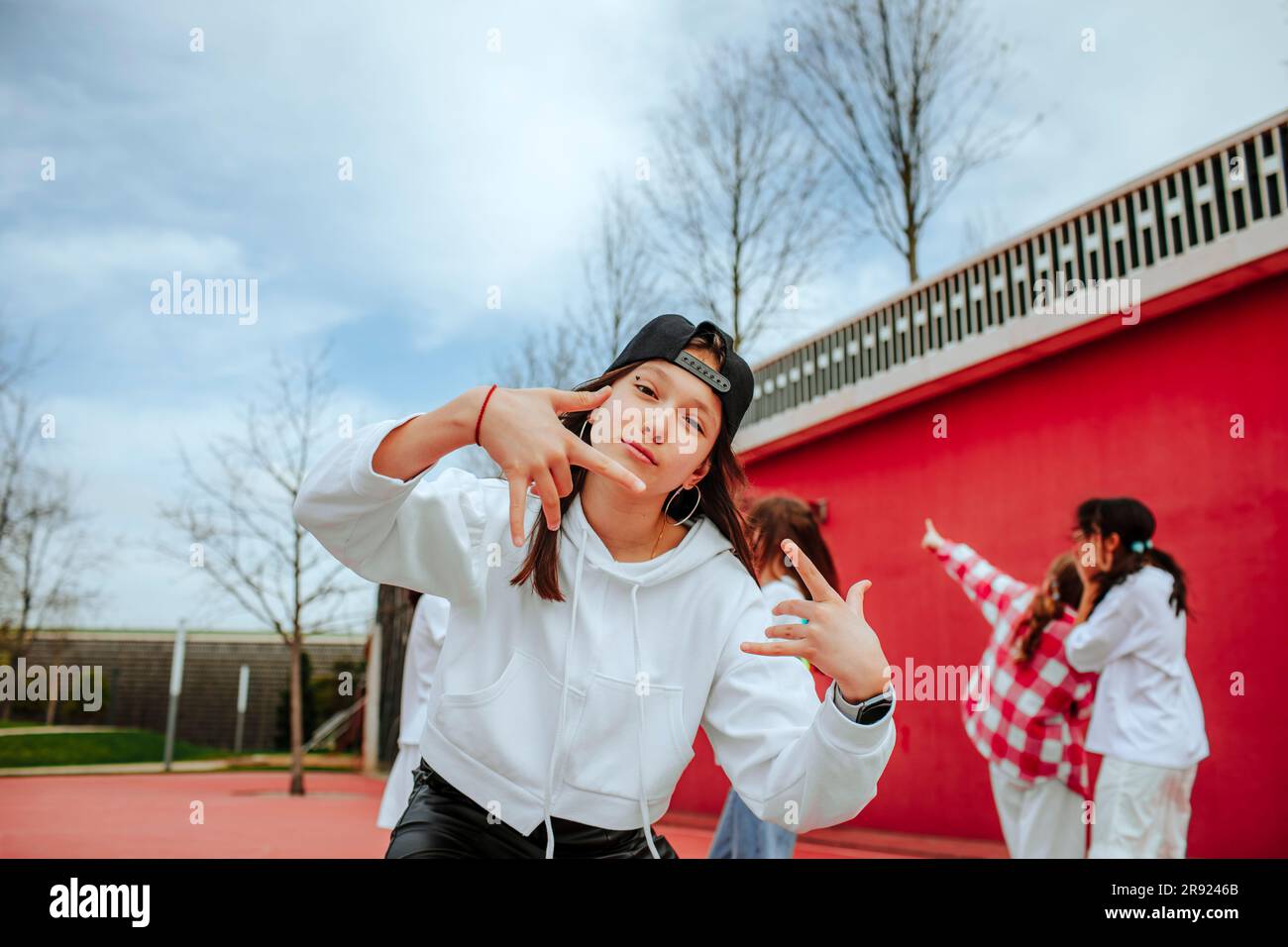 Teenage girl gesturing horn sign playing with friends at playground ...