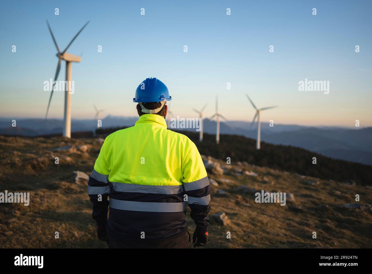 Engineer wearing reflective suit looking at wind turbines Stock Photo ...
