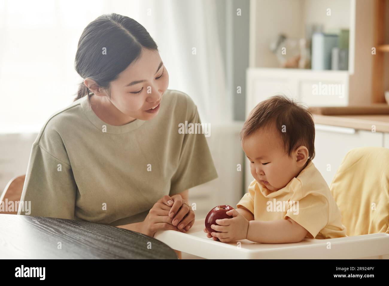 Mother talking to daughter holding apple at home Stock Photo - Alamy