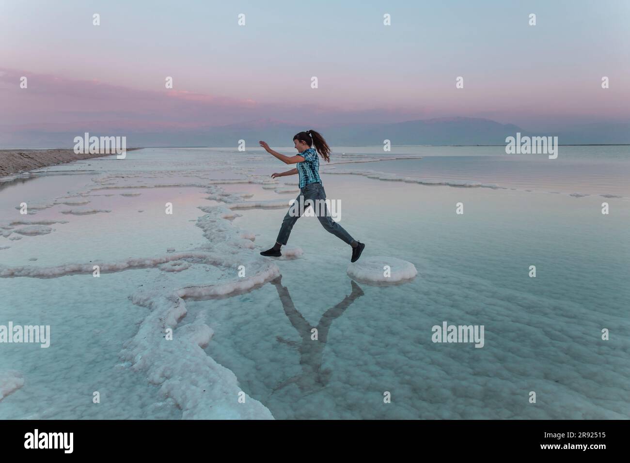 Young woman jumping on salt formations in dead sea at sunset Stock ...