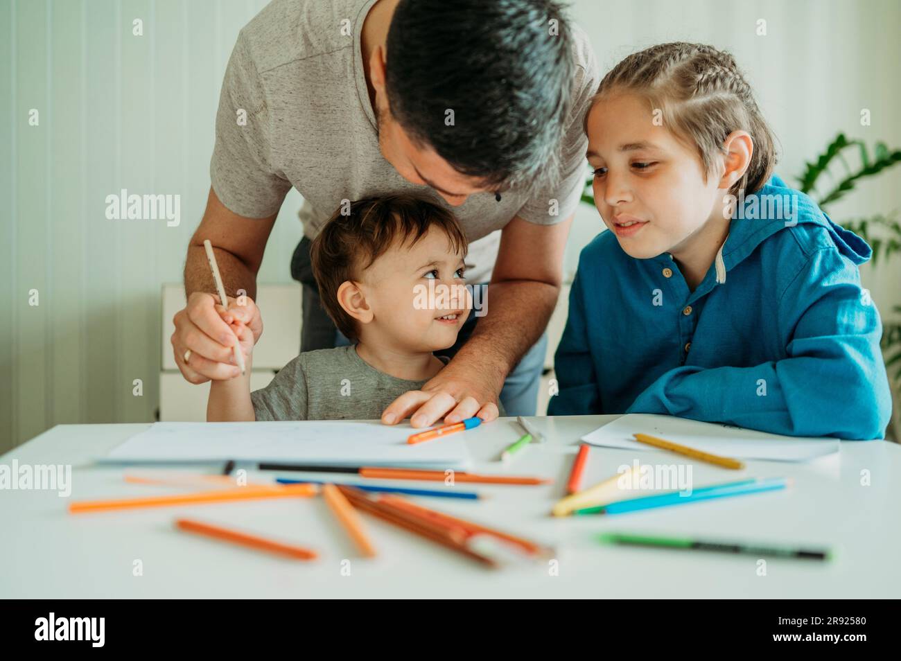 Father assisting sons to draw at home Stock Photo - Alamy