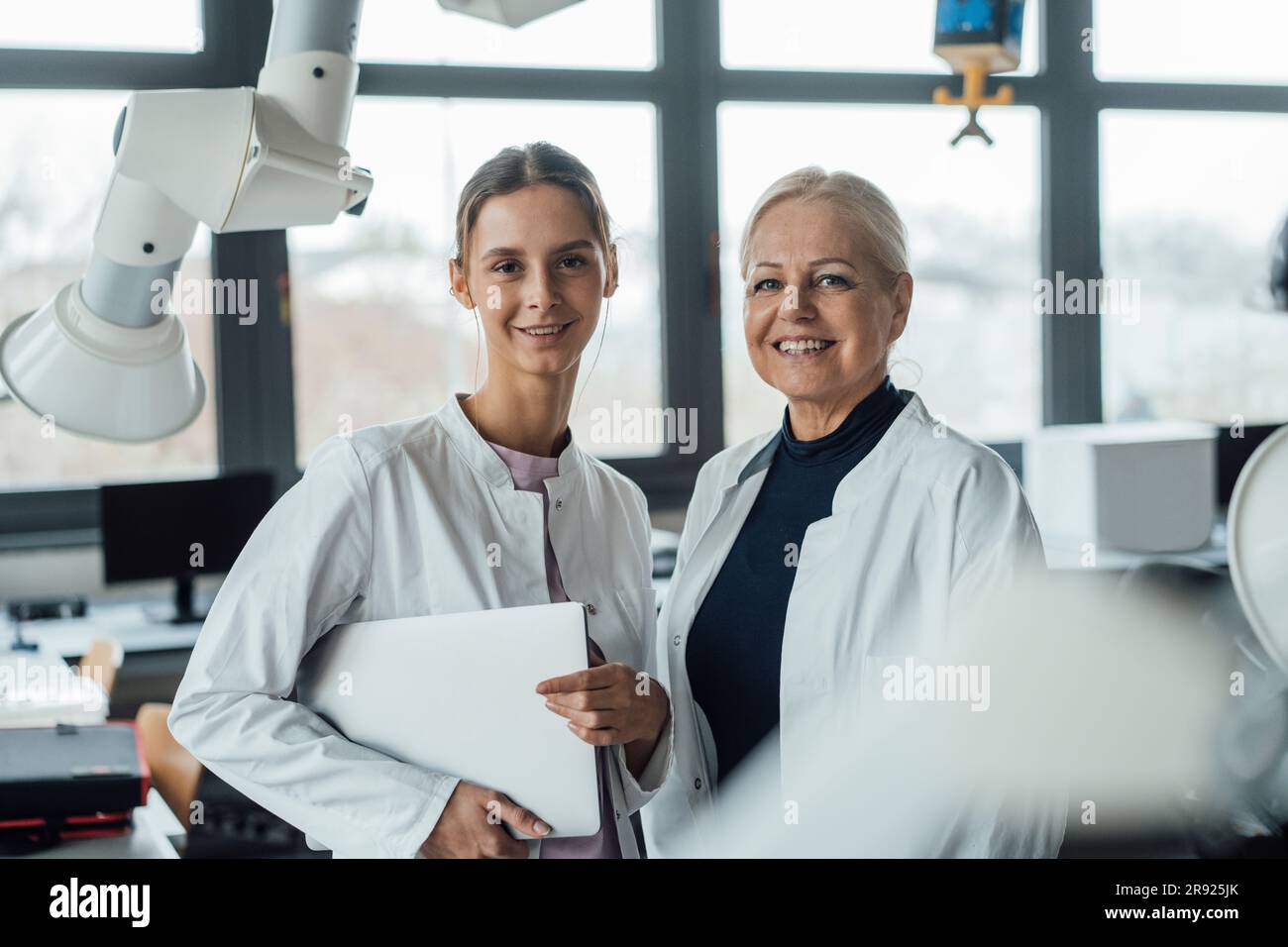Happy scientists standing together by robotic arm in laboratory Stock ...