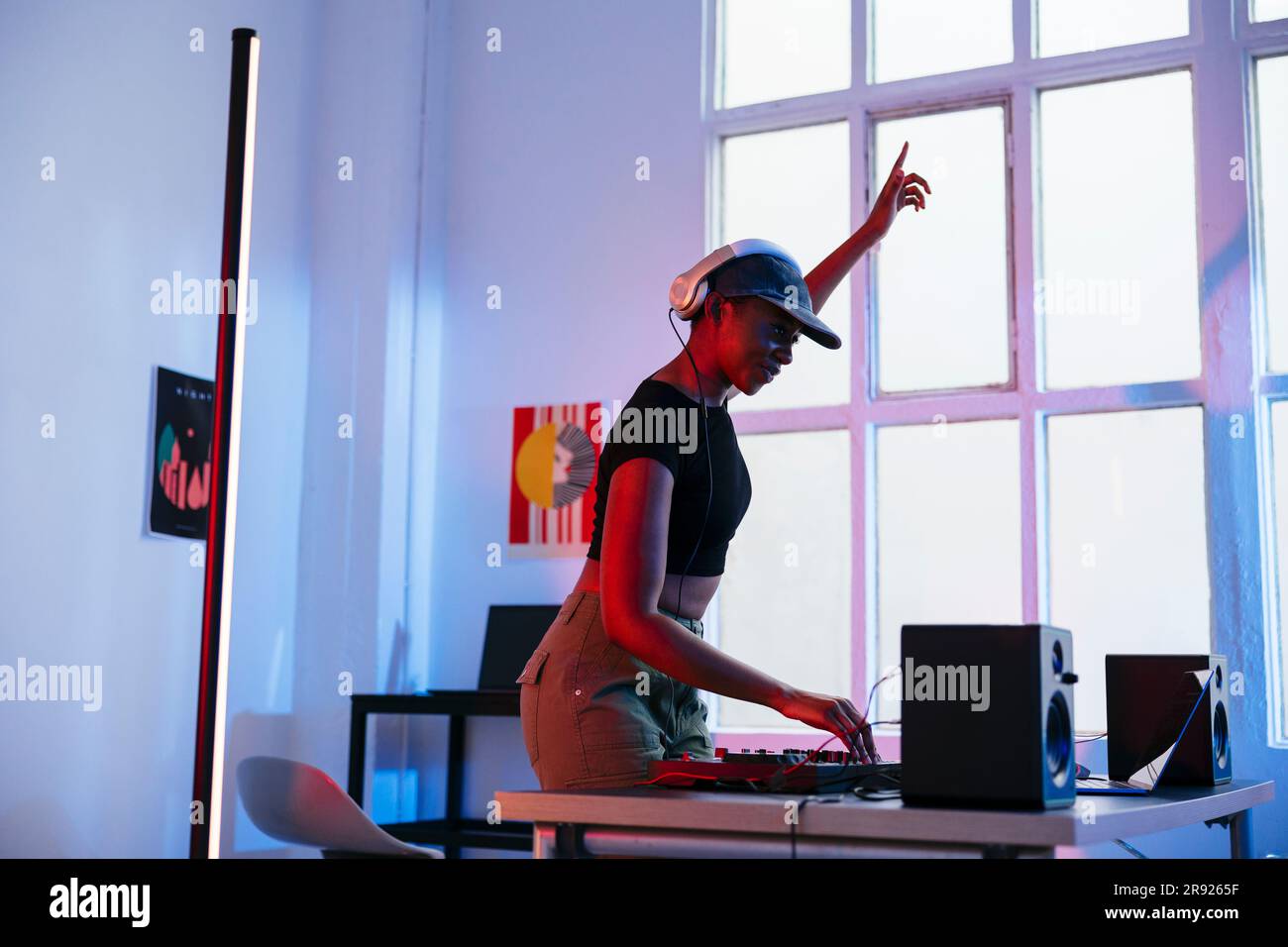 Smiling young DJ with arm raised operating sound mixer Stock Photo - Alamy