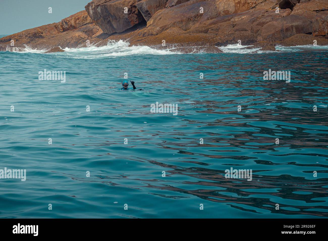 A young male diver is standing confidently in a body of water, wearing ...