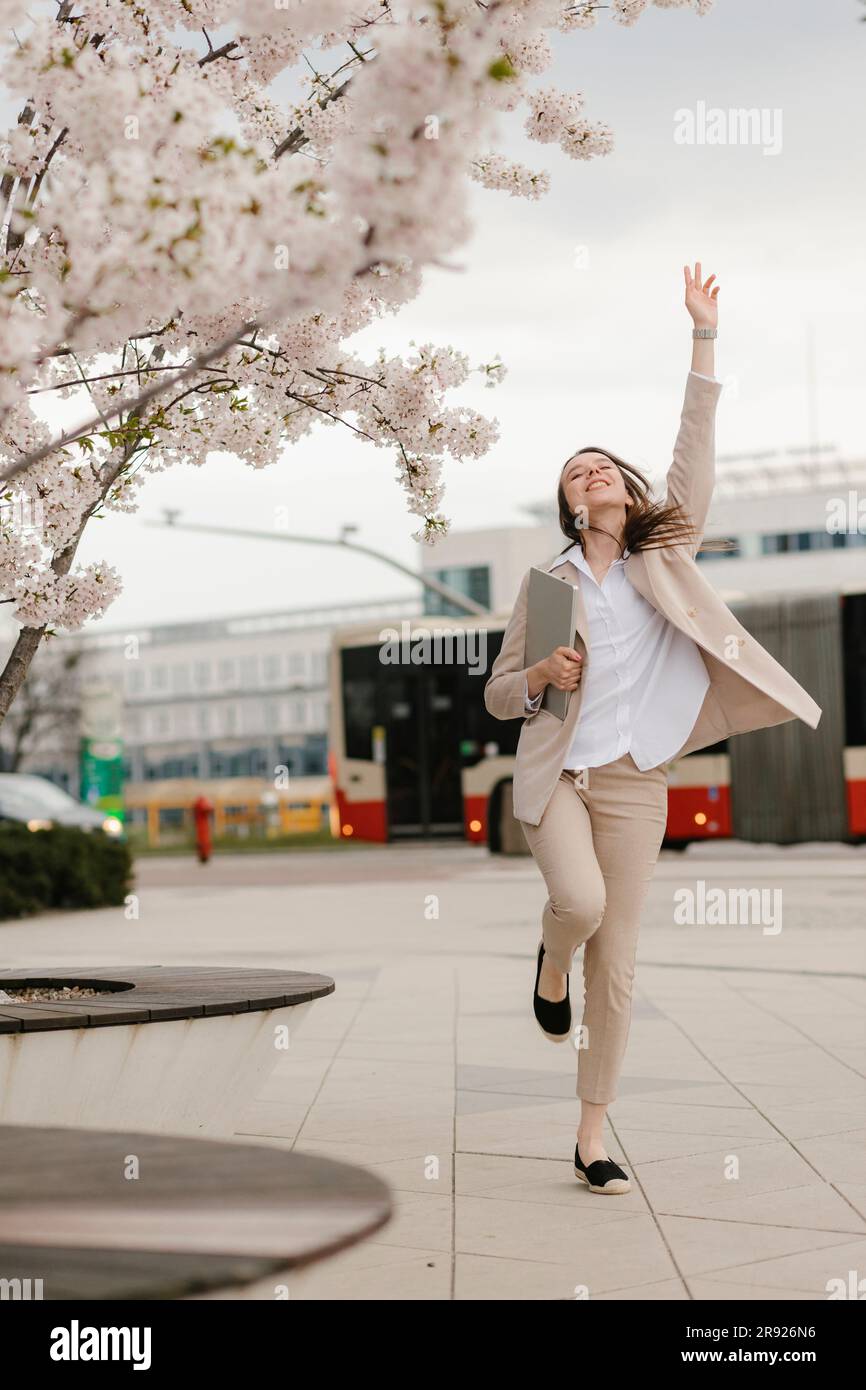 Cheerful businesswoman jumping by cherry blossom flower tree Stock ...
