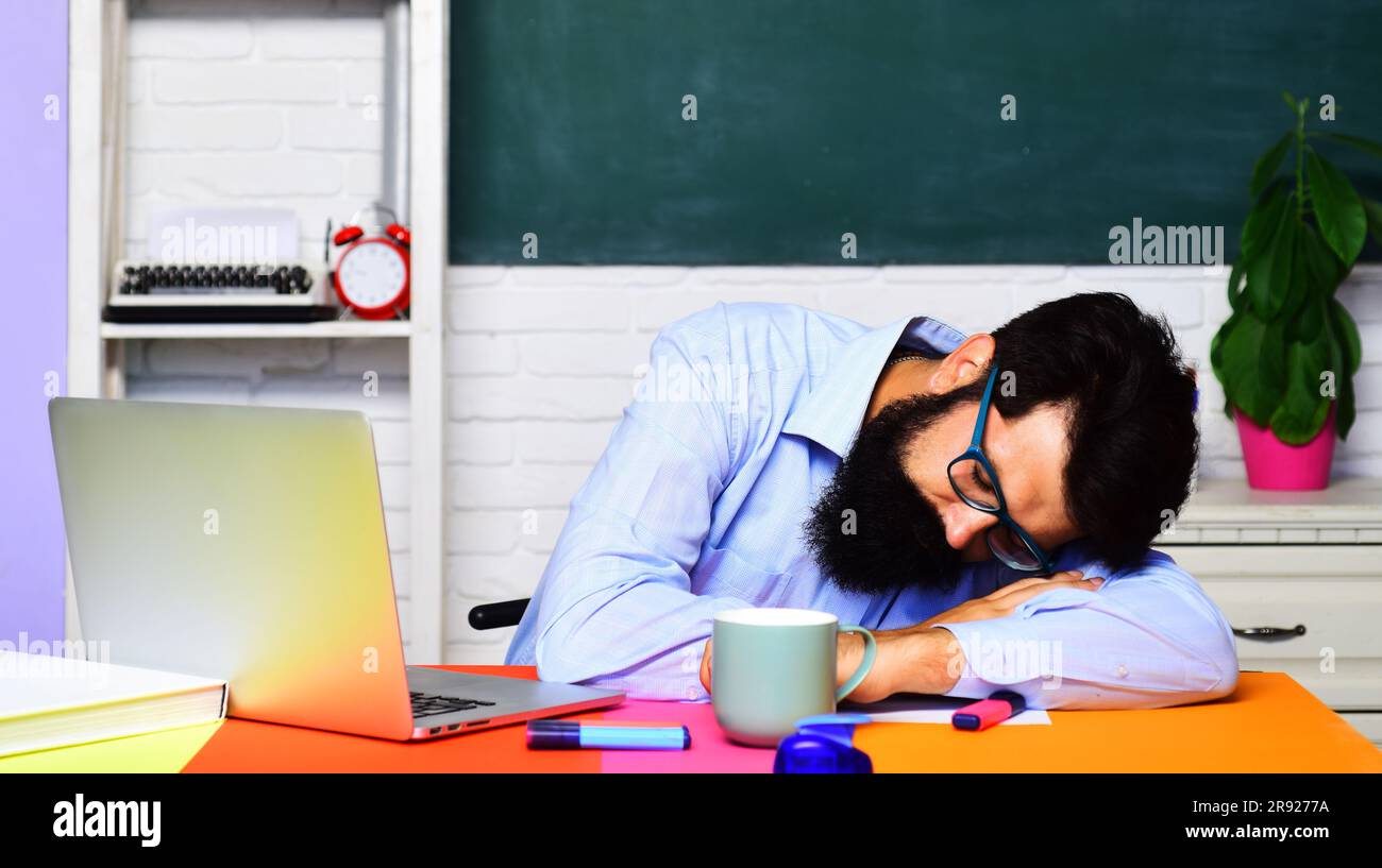 Tired overworked teacher sleeping on desk in classroom. School job ...