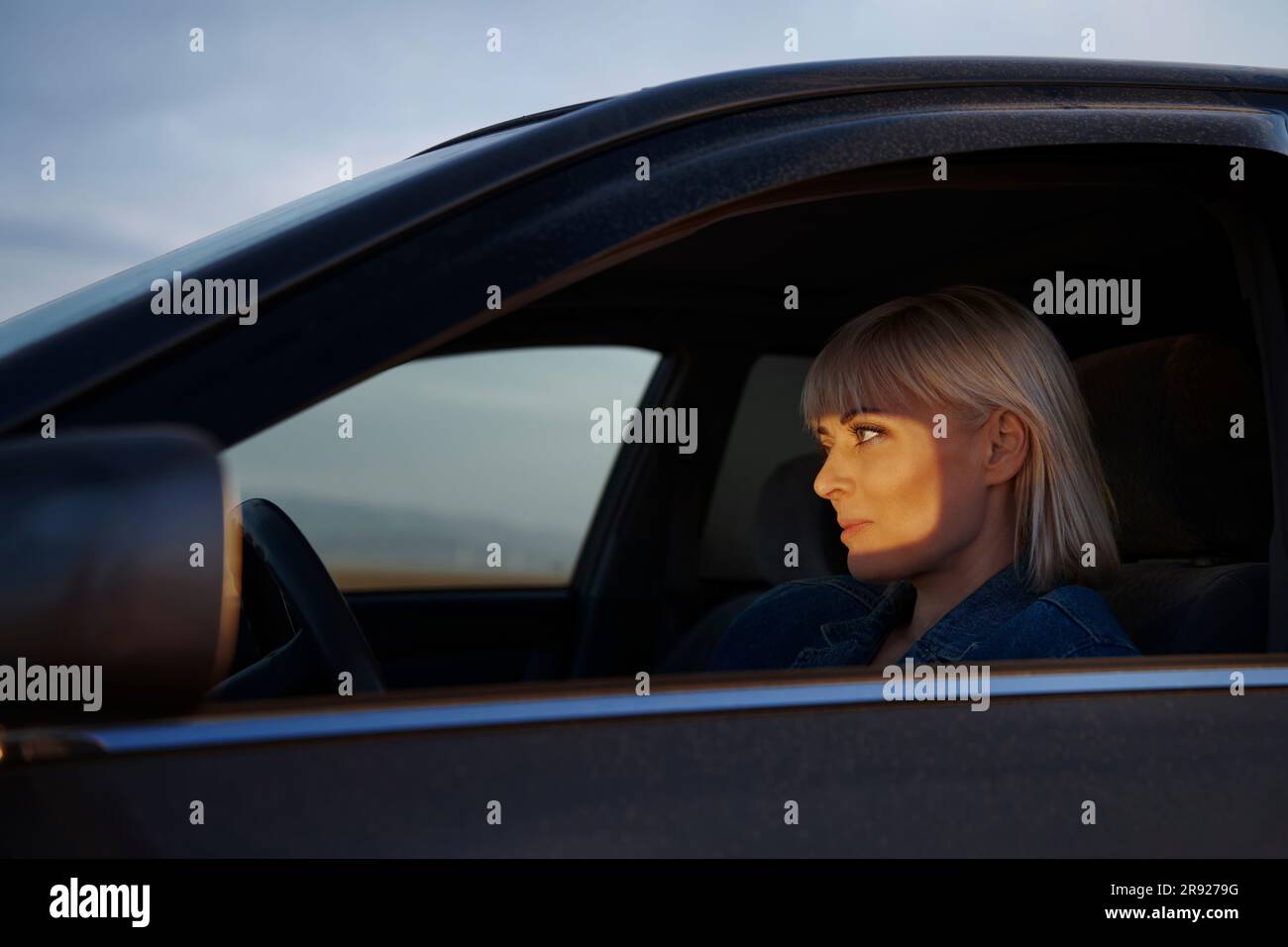 Blond woman driving car seen through window Stock Photo - Alamy