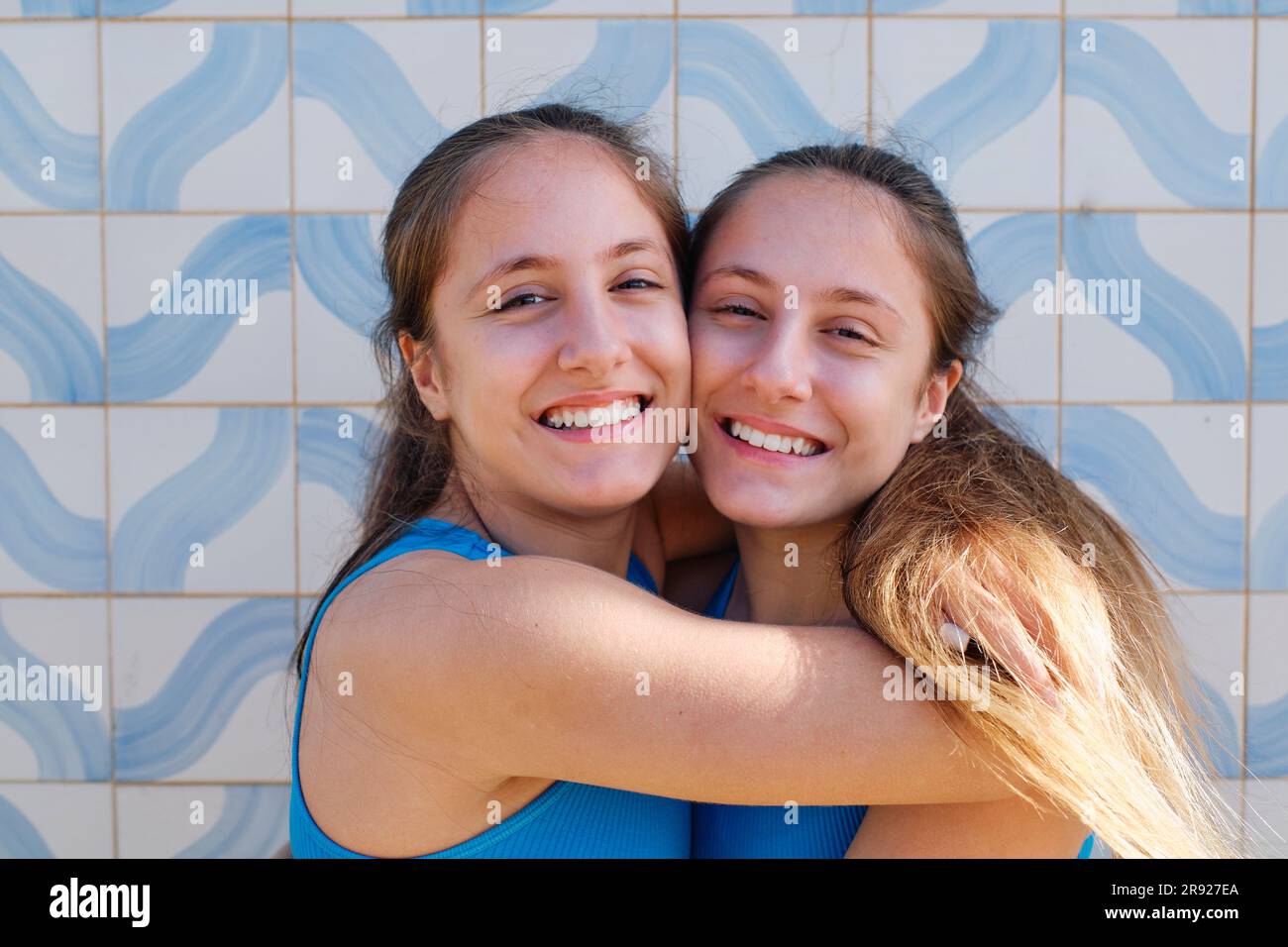 Loving twin sisters hugging in front of wall Stock Photo - Alamy