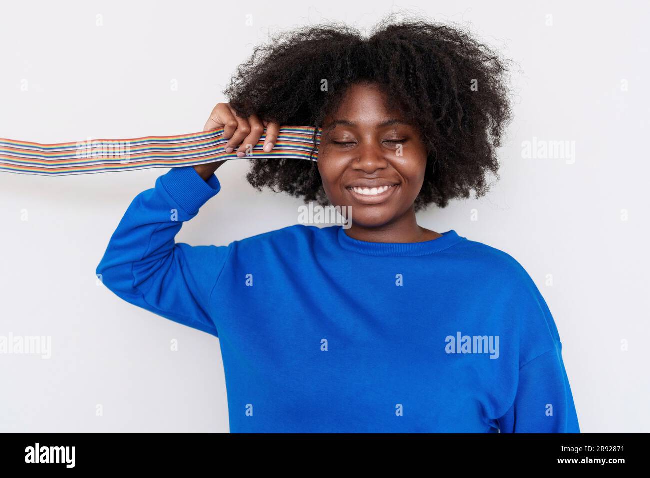 Young Afro woman holding cables near head against white background ...