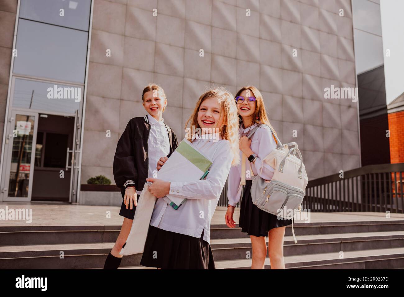 Smiling friends standing in front of school building Stock Photo - Alamy