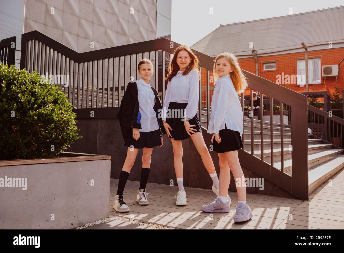 Smiling school girls standing near stairs on school yard Stock Photo ...