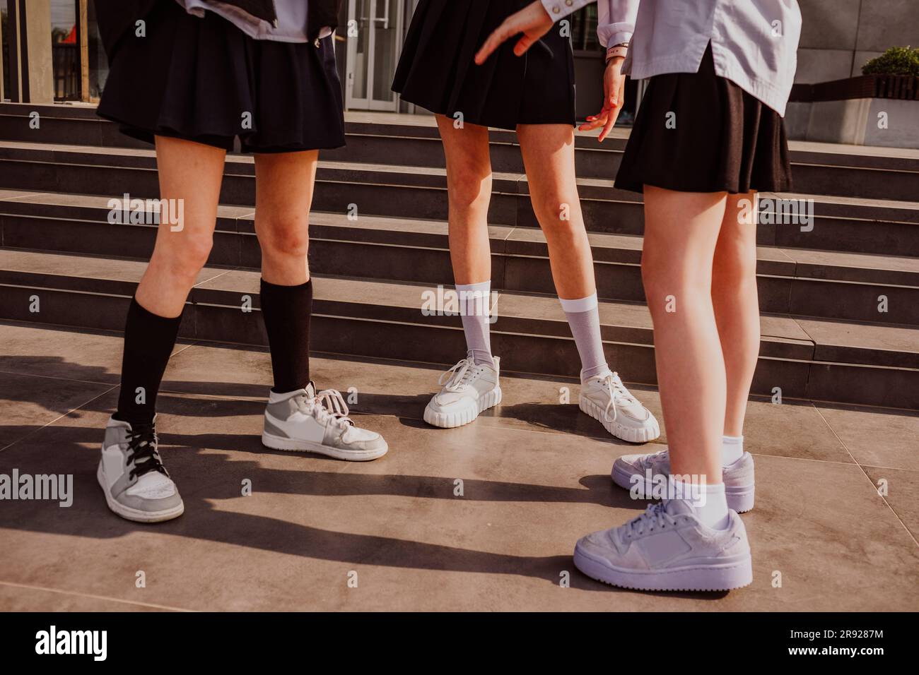Female friends wearing shoes standing near steps Stock Photo - Alamy